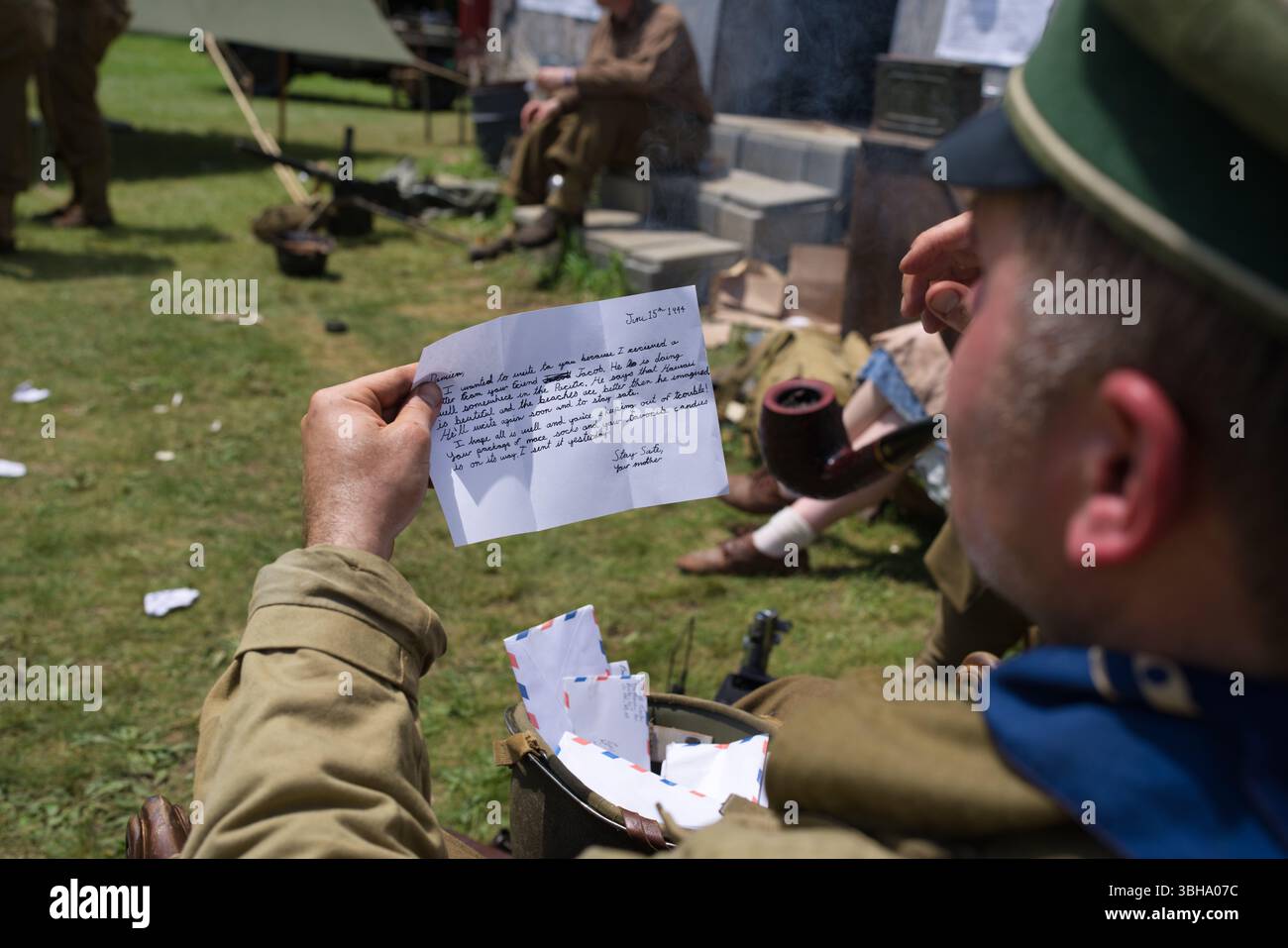 Close-up view of a soldier in WWII-era uniform reading a handwritten ...