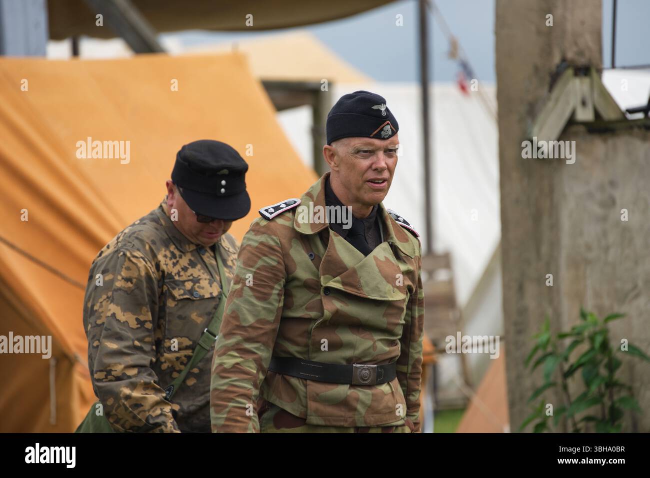Two men in World War II-era German military uniforms are standing ...