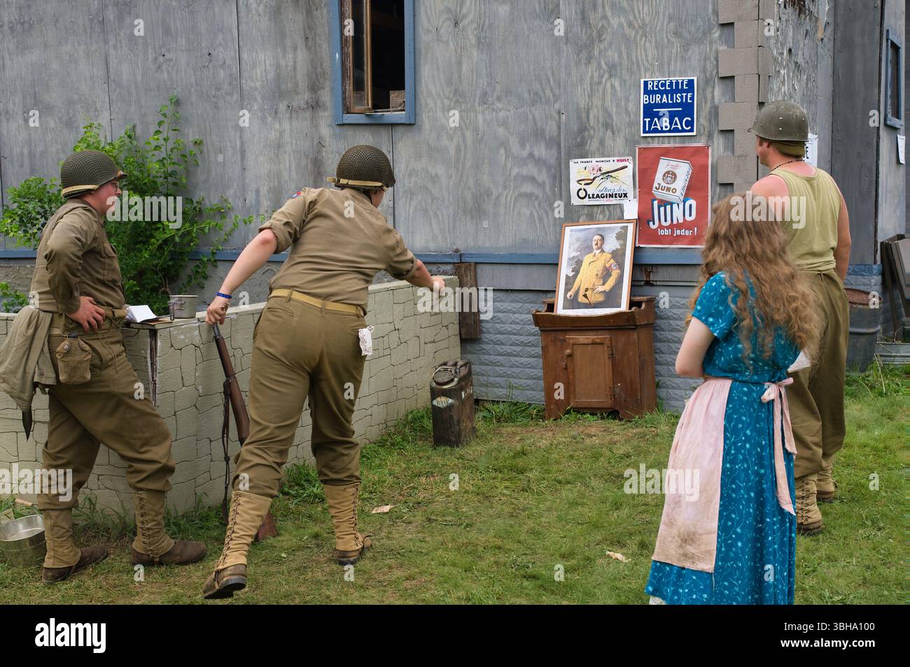 Two WWII reenactors in US Army uniforms inspect a small, framed ...
