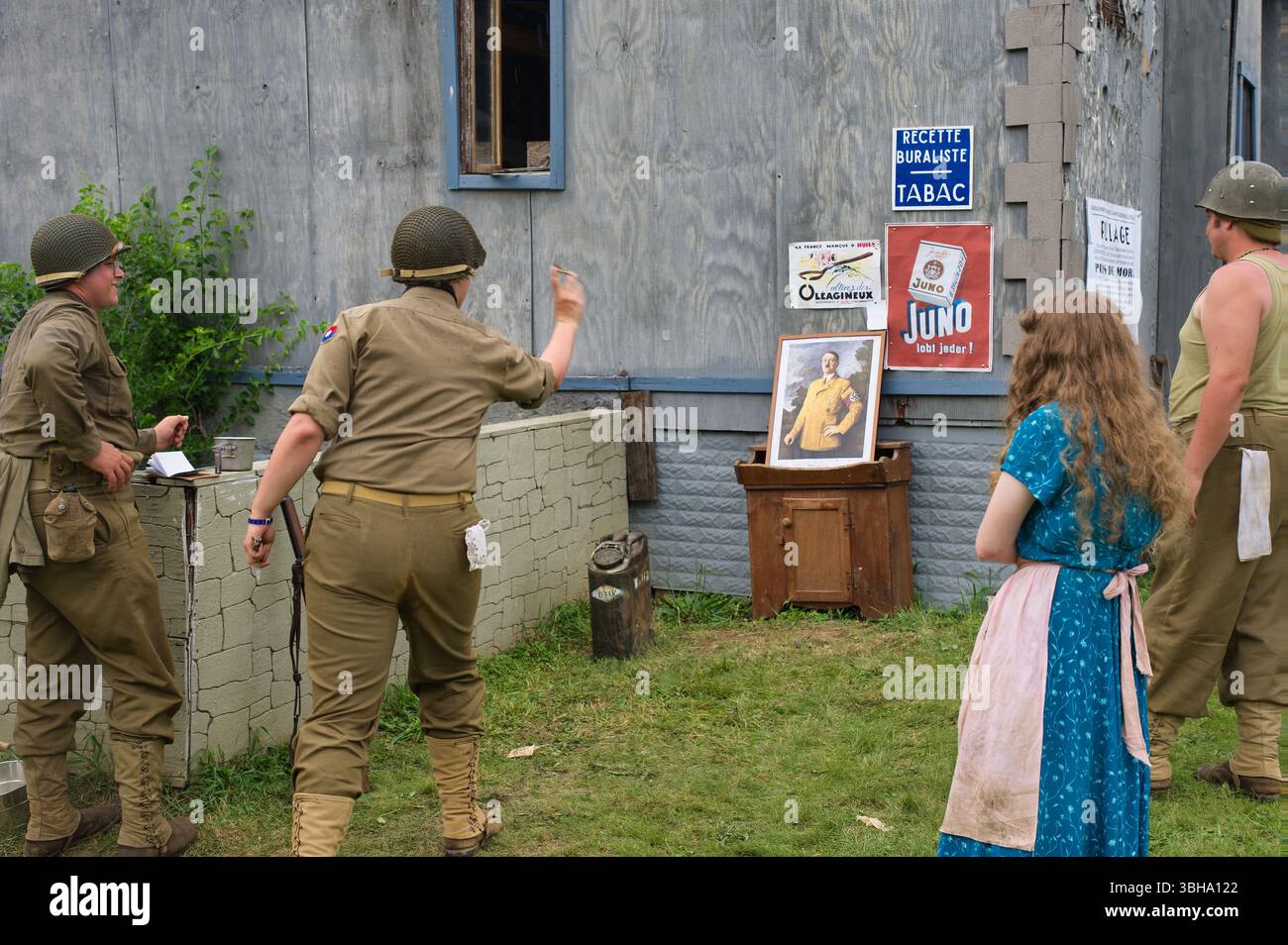 World War II reenactors in period uniforms are shown near a building ...