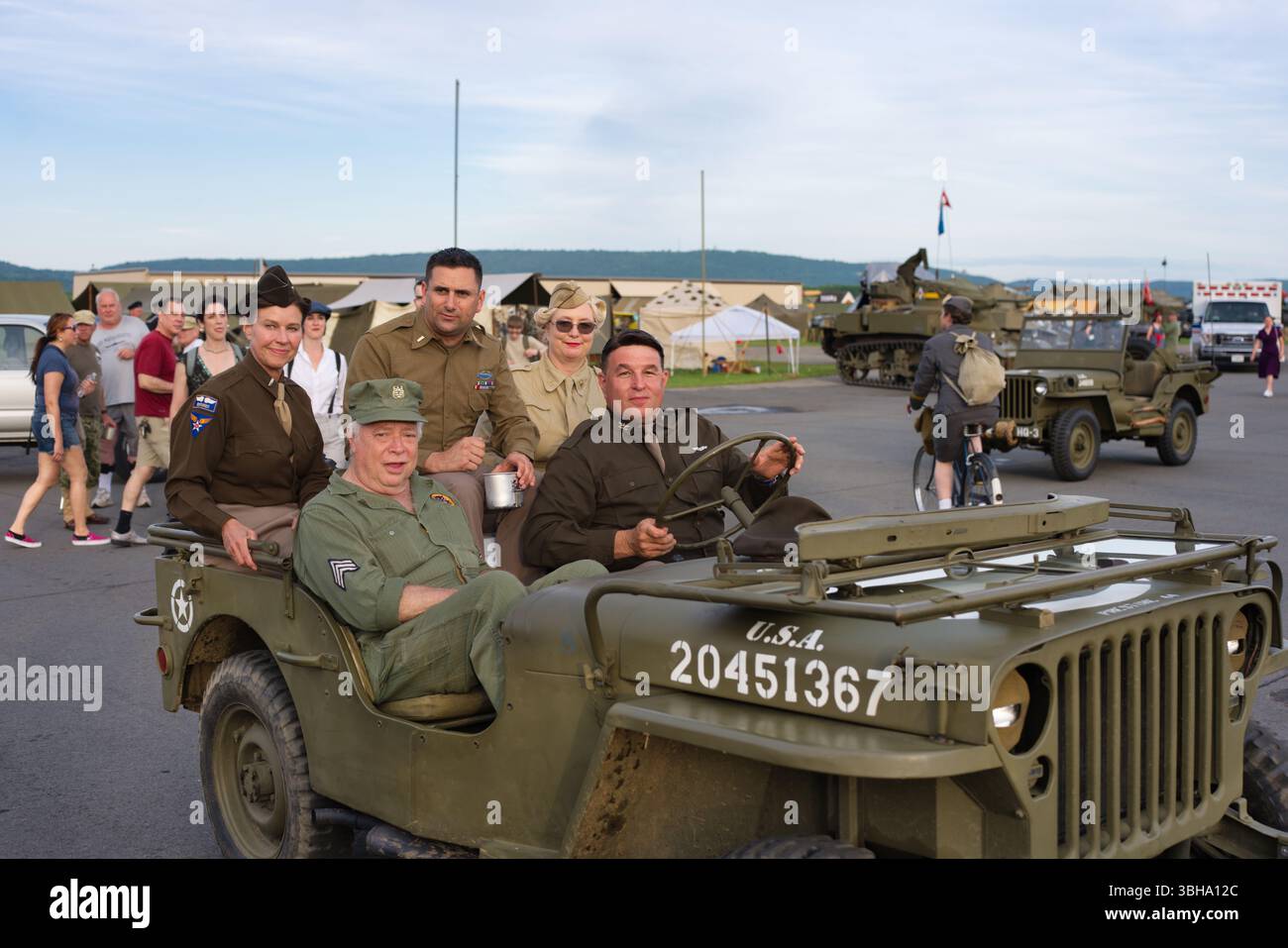 Six people in WWII-era military and civilian attire are seated in a ...