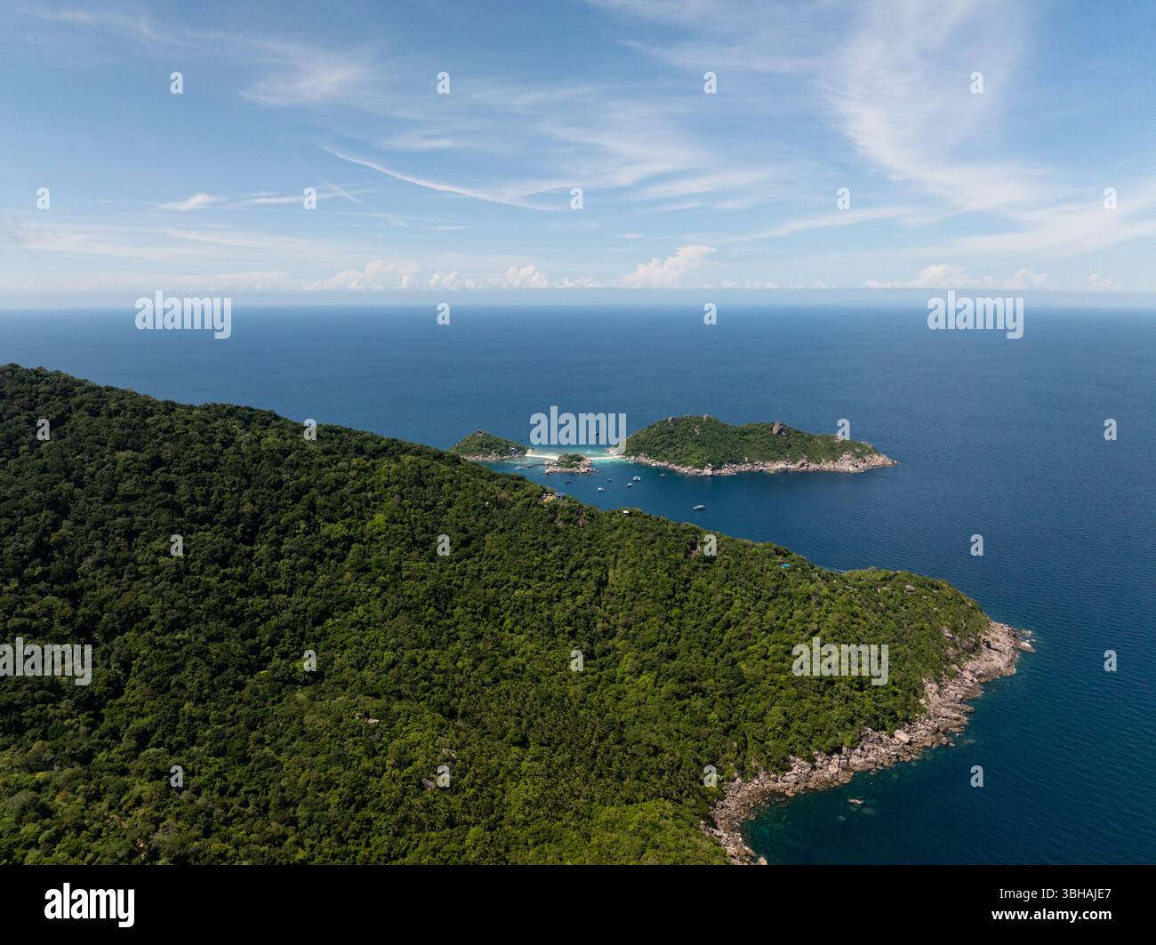 Tropical island with dense greenery surrounded by clear blue ocean ...