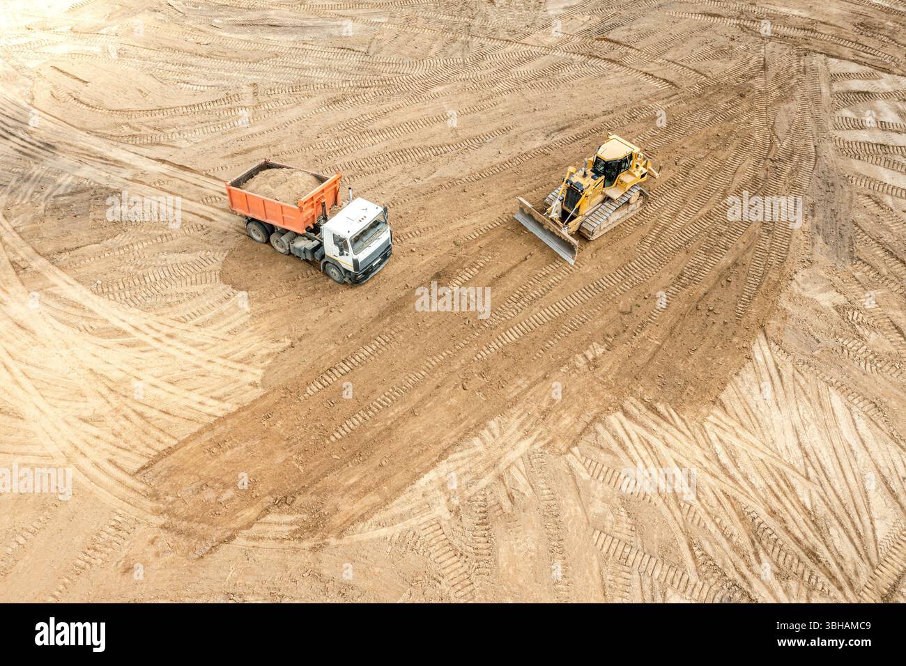 yellow bulldozer and dump truck works at construction site. top view ...