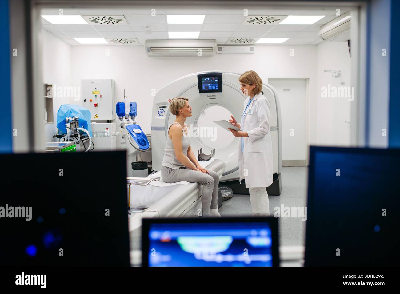 Doctor explaining CT scan results to female patient in imaging room ...