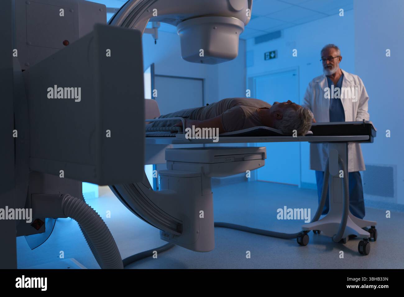 Male patient undergoing X-ray examination using tilting radiographic ...