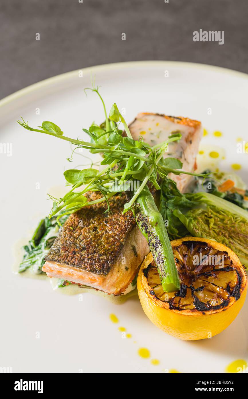 Grilled salmon fillet with charred lemon and greens on plate Stock ...