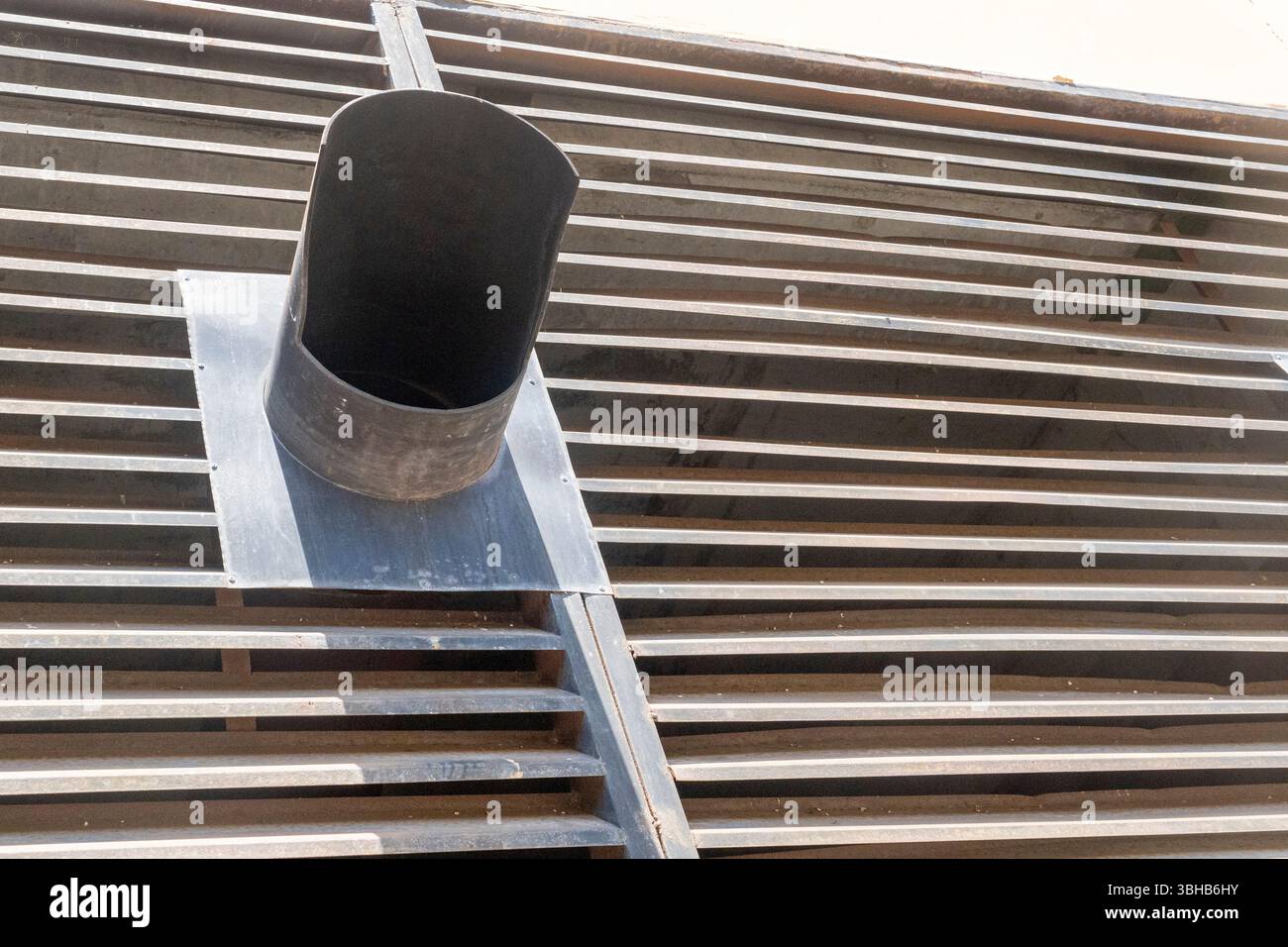 Metal pipe protruding from a roof of a building. The pipe is black and ...
