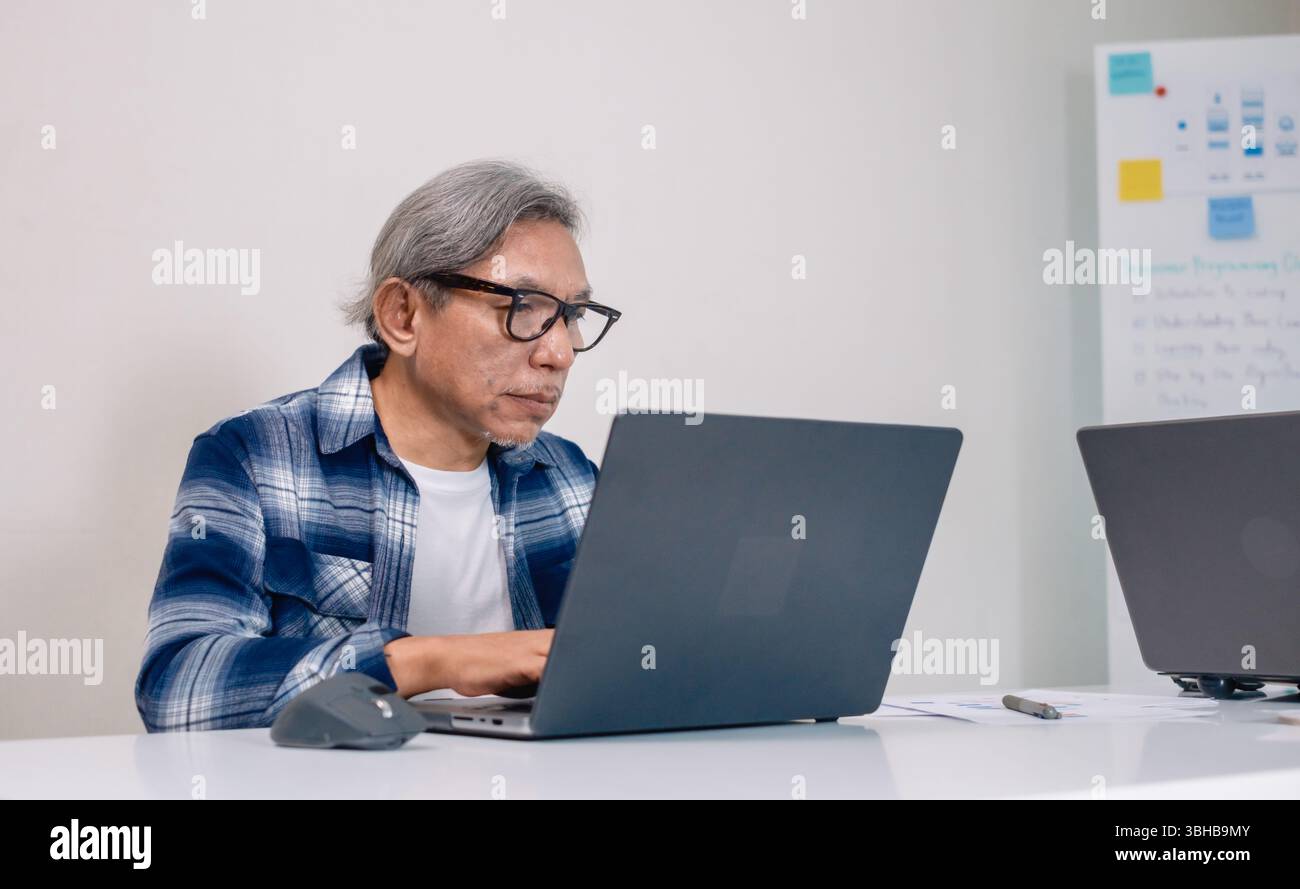 Senior male participating in a computer programming bootcamp, improving skills and learning ...