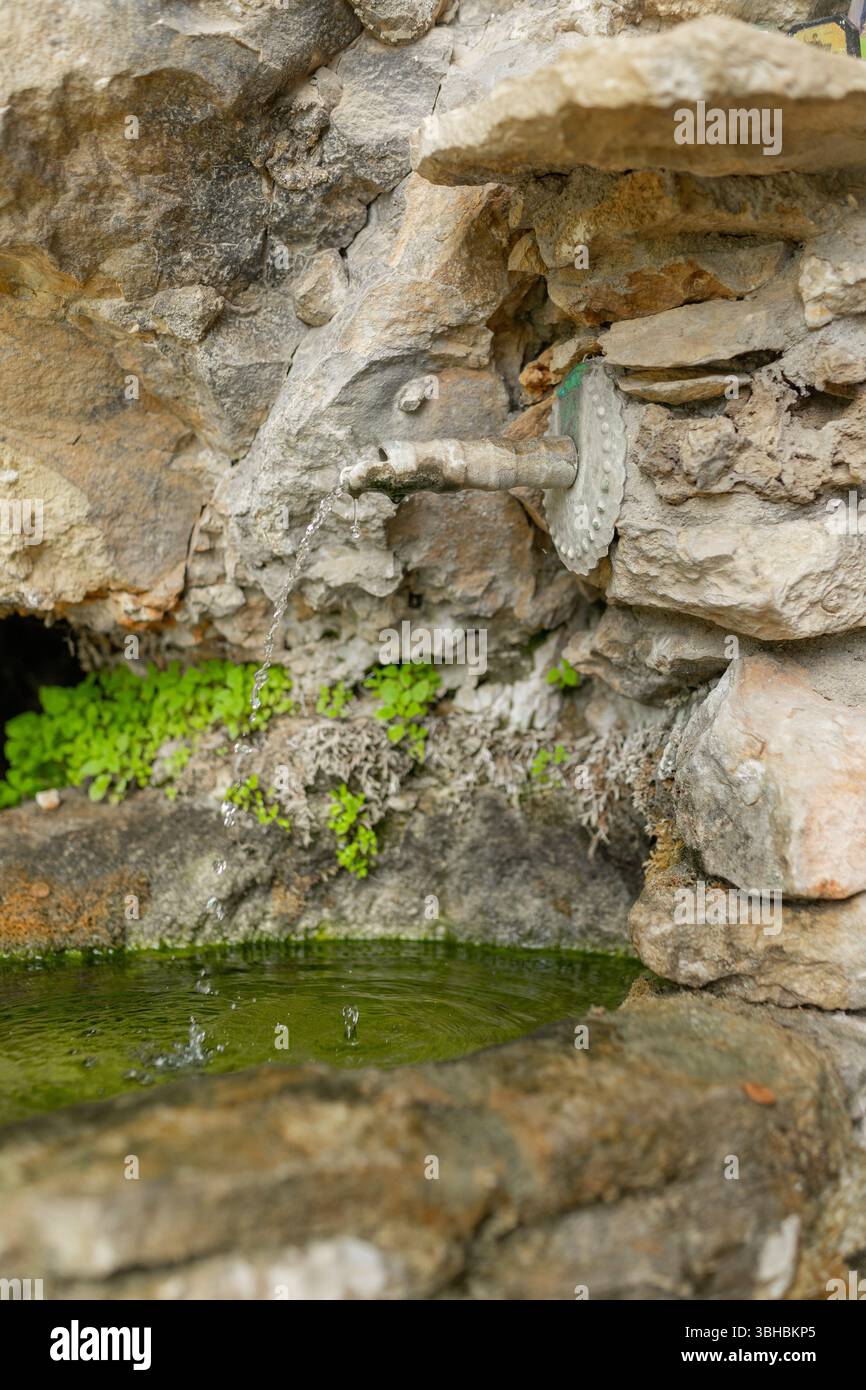 Rustic fountain made of weathered stone with dripping pipe and water ...