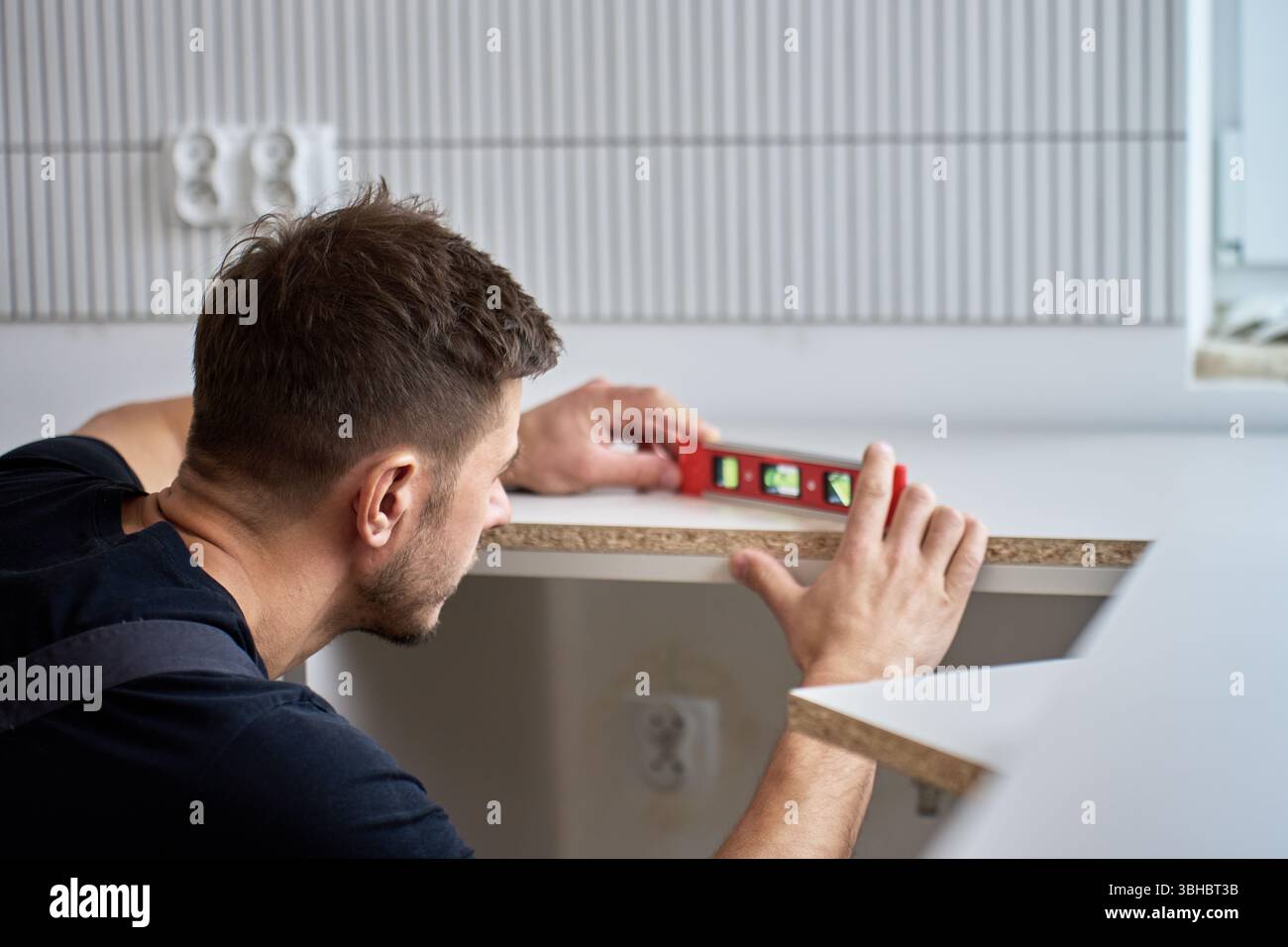 Man uses spirit level to align kitchen countertop panel during ...