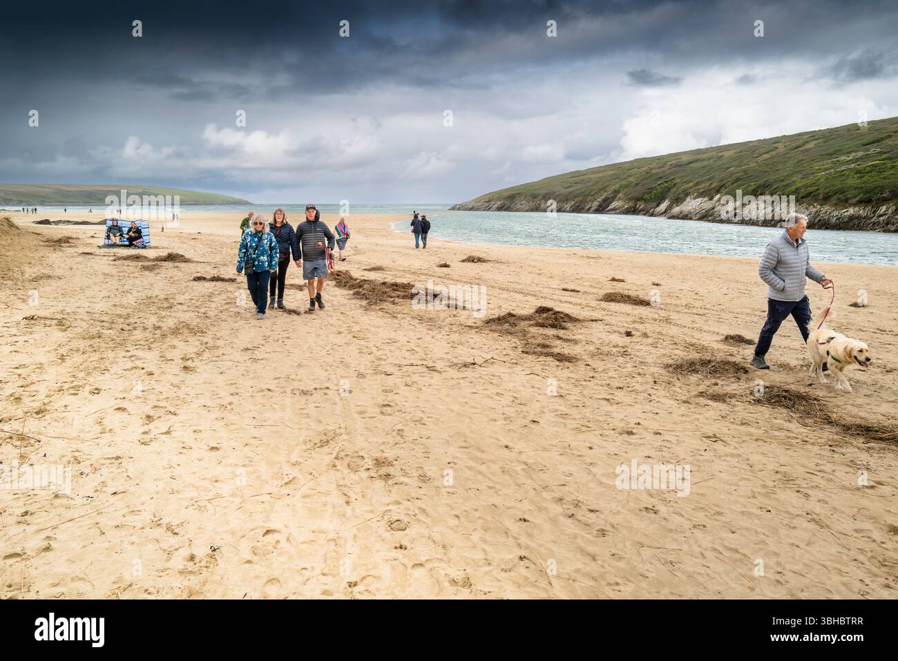 People enjoying a brisk walk along the wild windswept Crantock Beach in ...