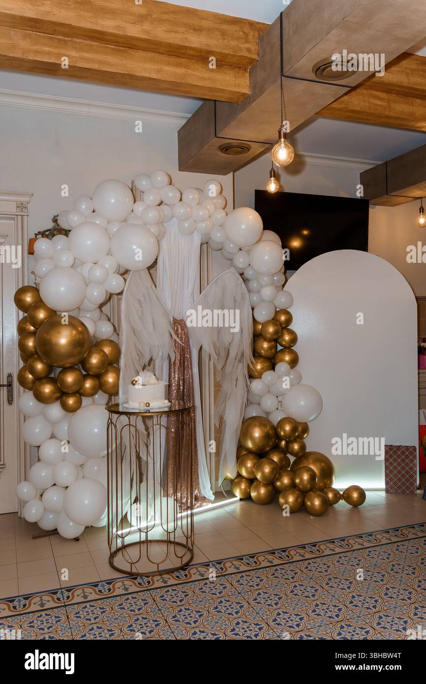 A captivating angel-themed party setup features a large white and gold ...