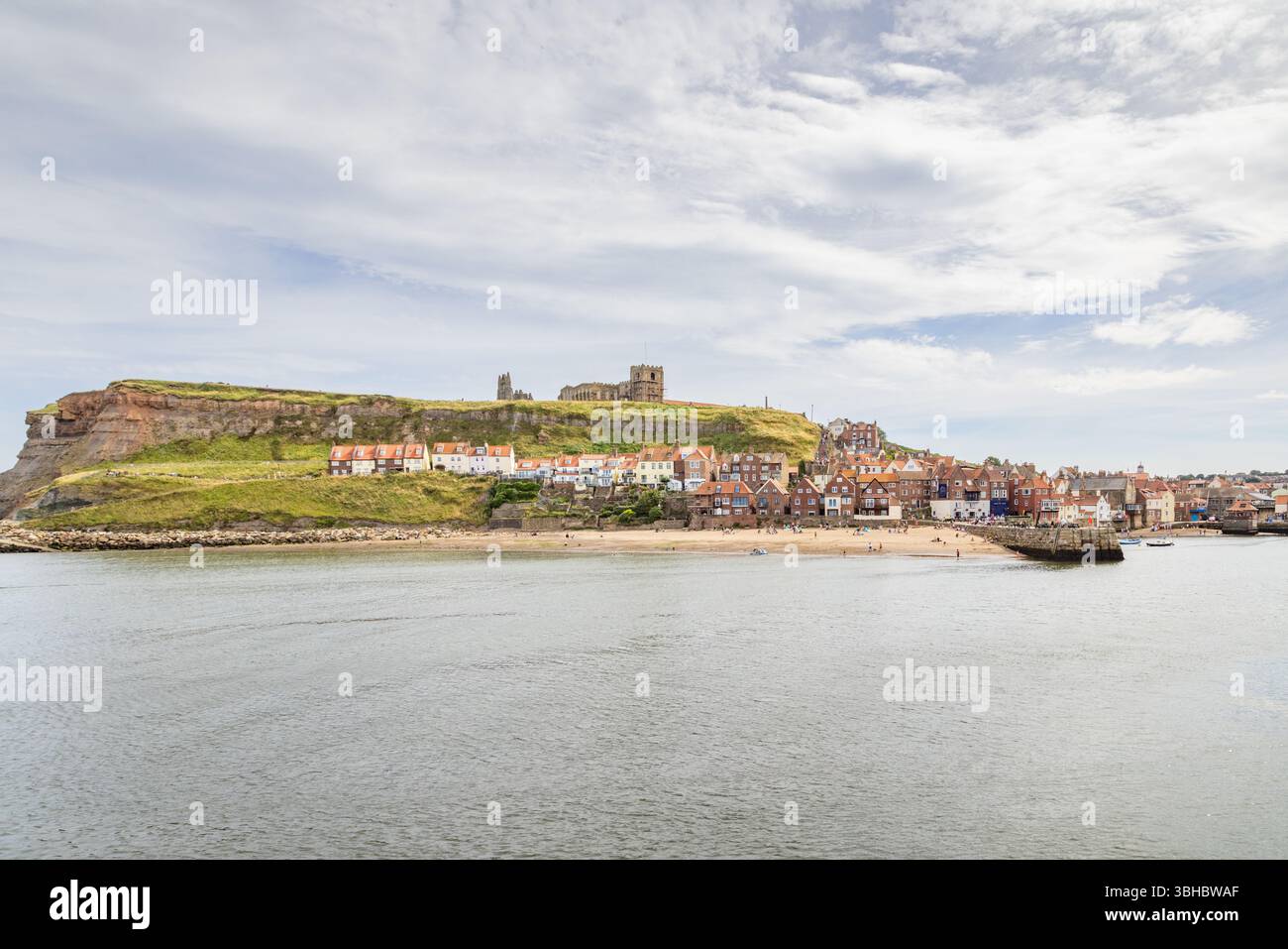 Whitby’s harbour, East Cliff rises behind red roofed cottages, with ...