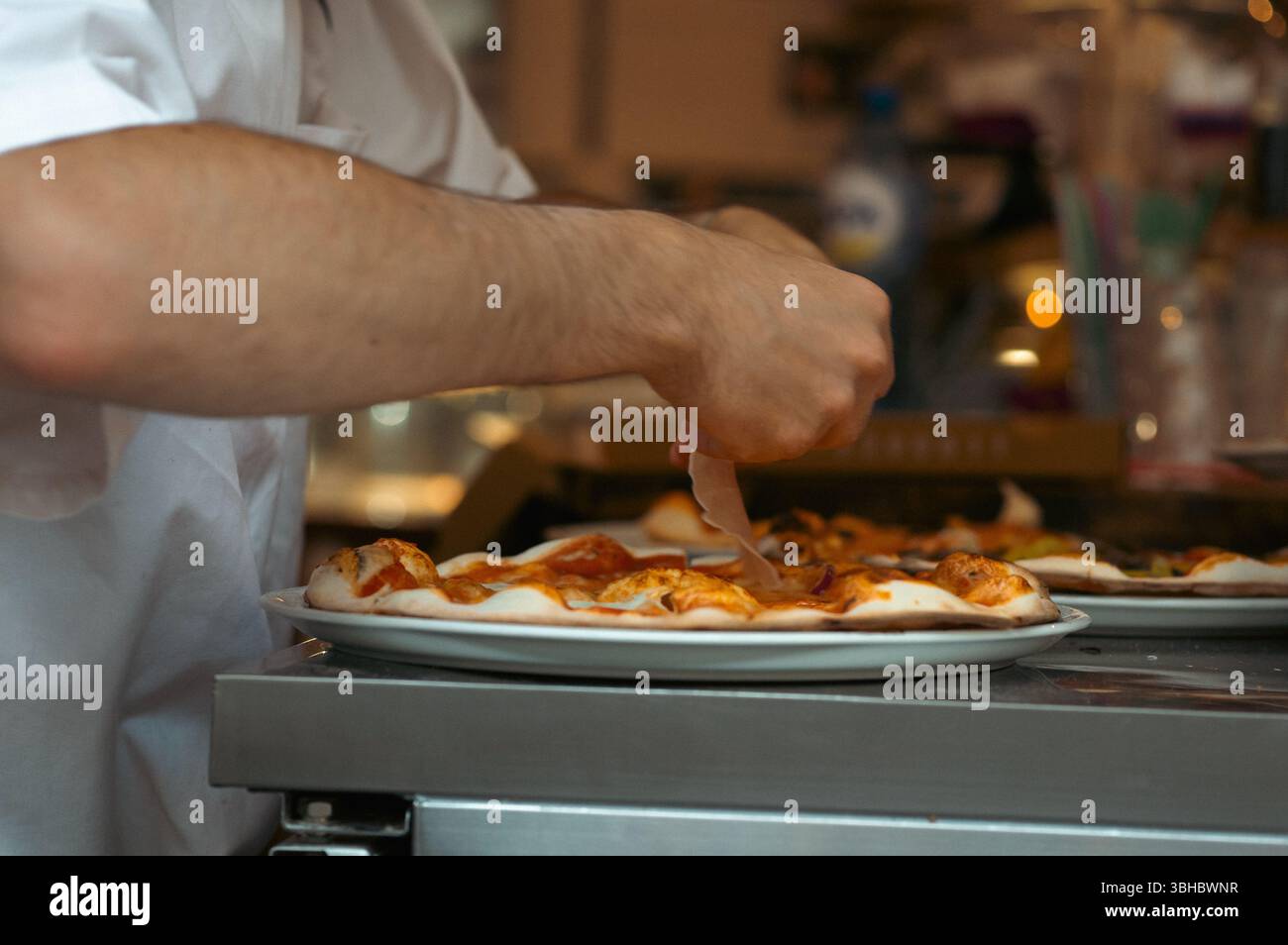 Chef slicing pizza at kitchen counter Stock Photo - Alamy