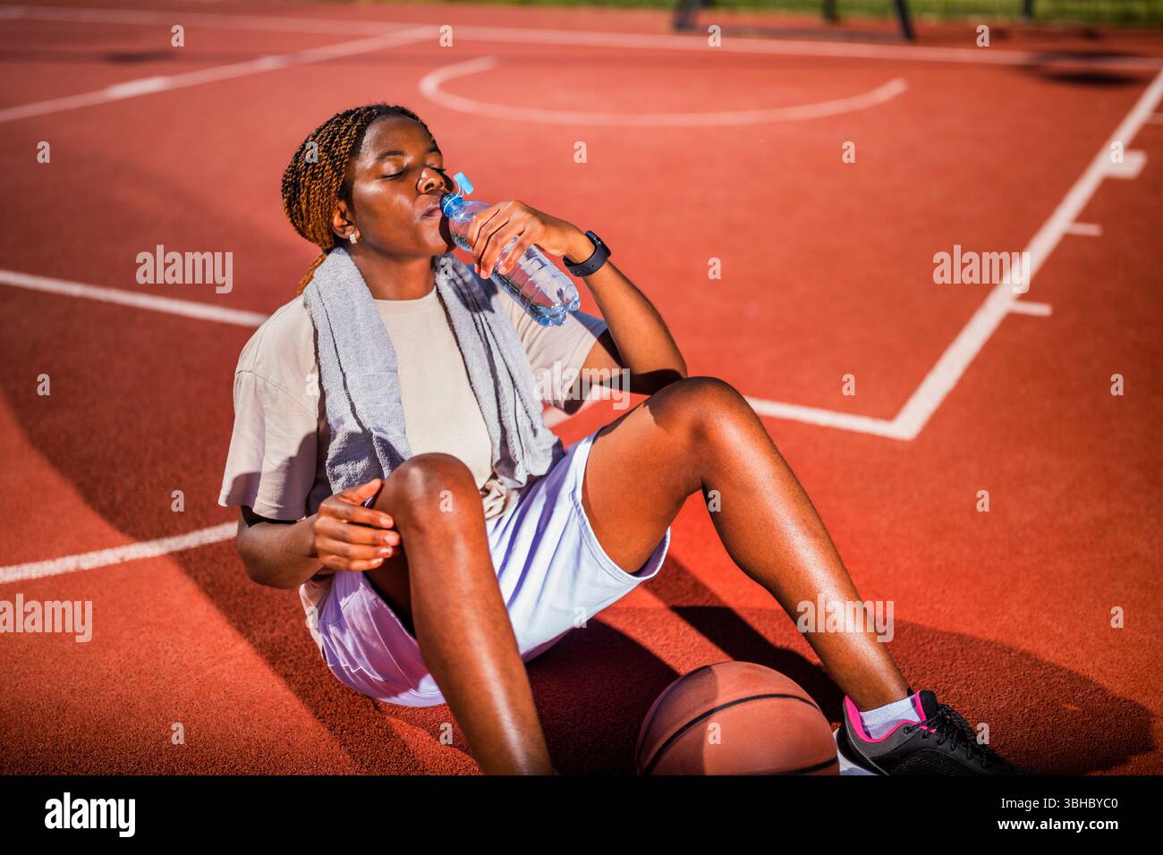 Young black woman practicing basketball alone at sports court in the ...