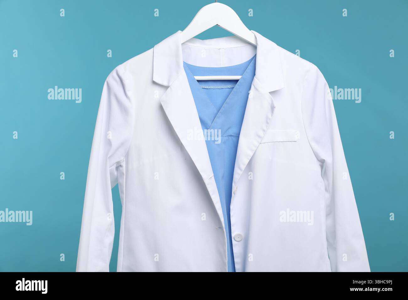 Doctor's coat on hanger against blue background Stock Photo - Alamy