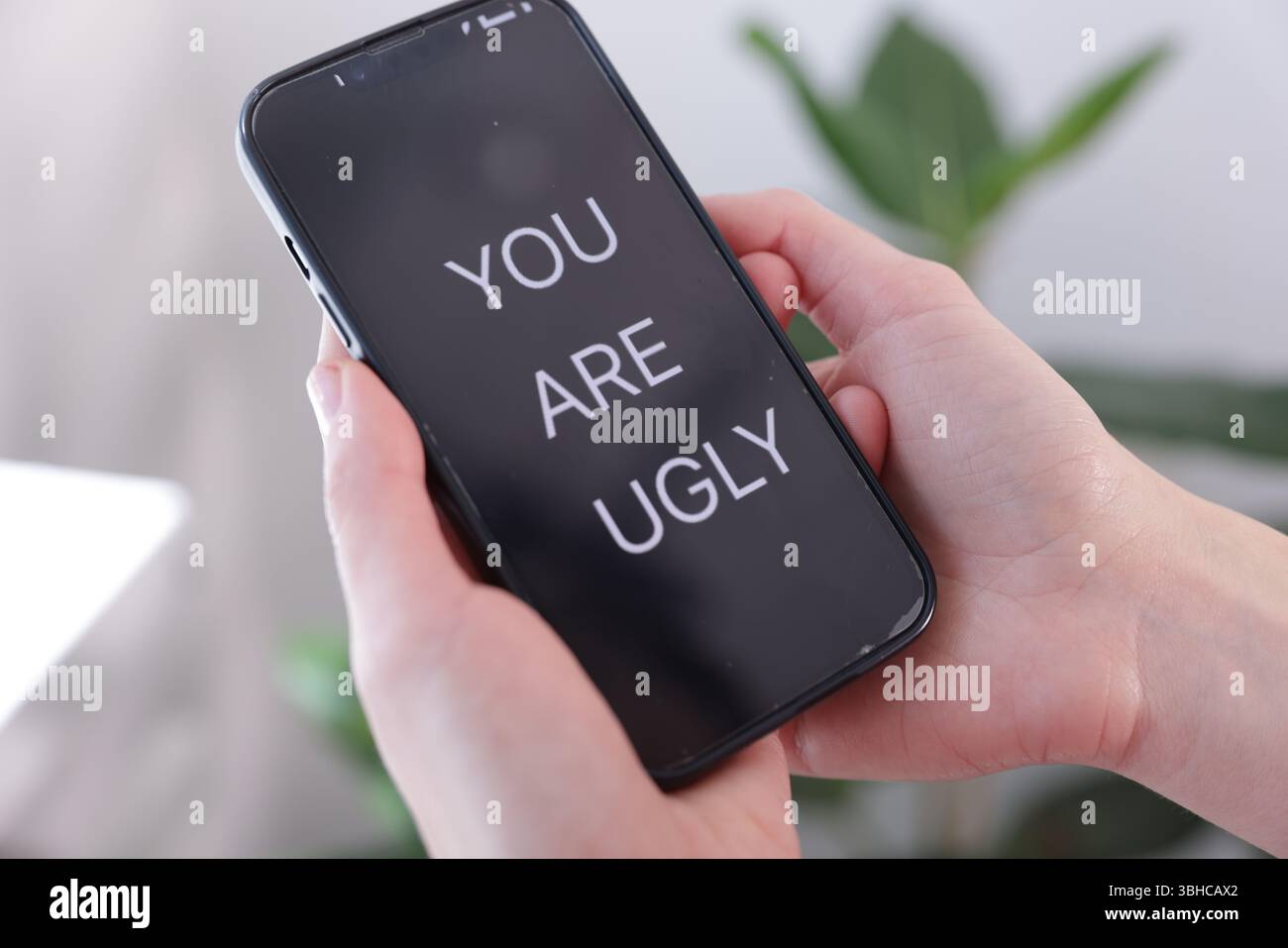Cyber bullying. Woman holding smartphone with text You Are Ugly on ...
