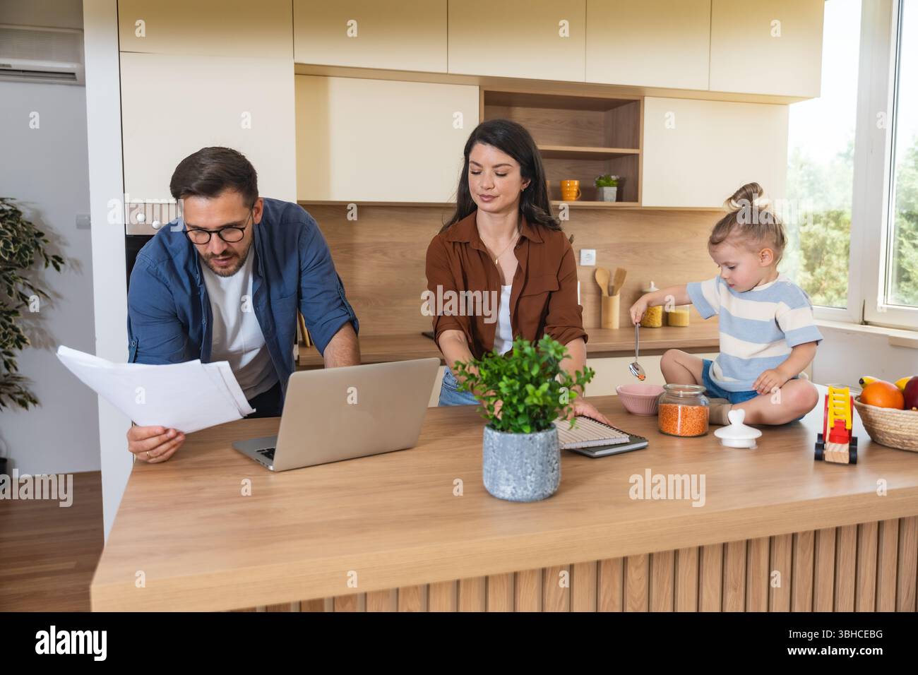 Joyful young family bonding in bright modern kitchen mother and daughter laughing while playing ...