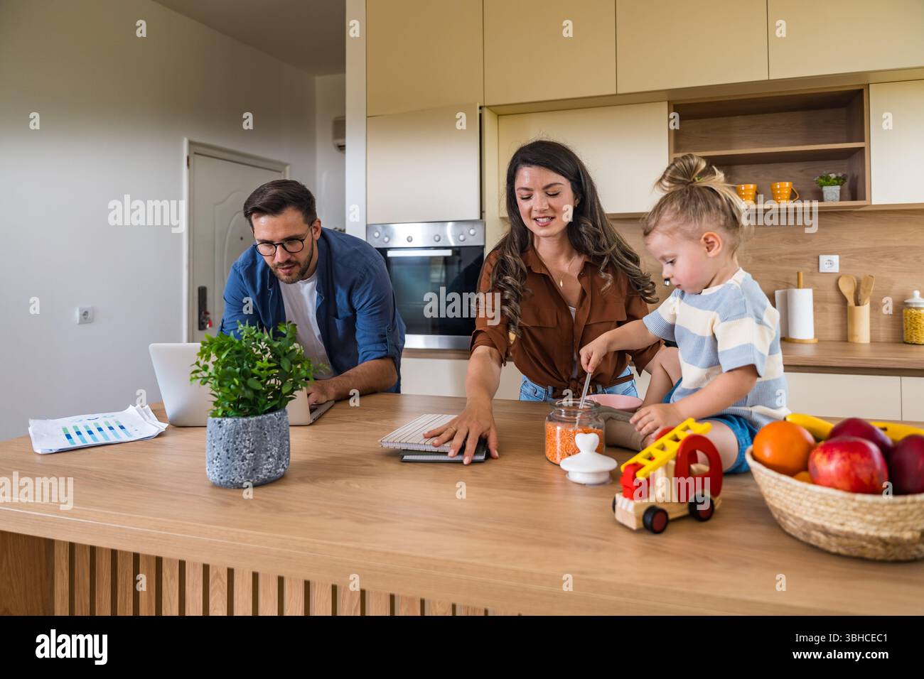 Joyful young family bonding in bright modern kitchen mother and daughter laughing while playing ...