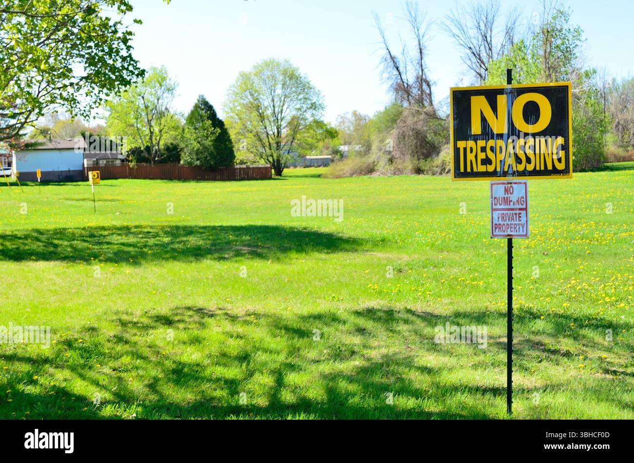 Series of No Trespassing signs across an open park with trees and ...