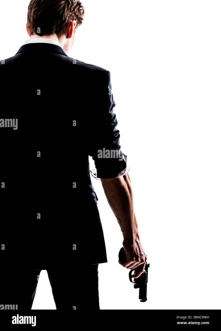 A man in a suit, seen from the back, holds a revolver by his side. The ...