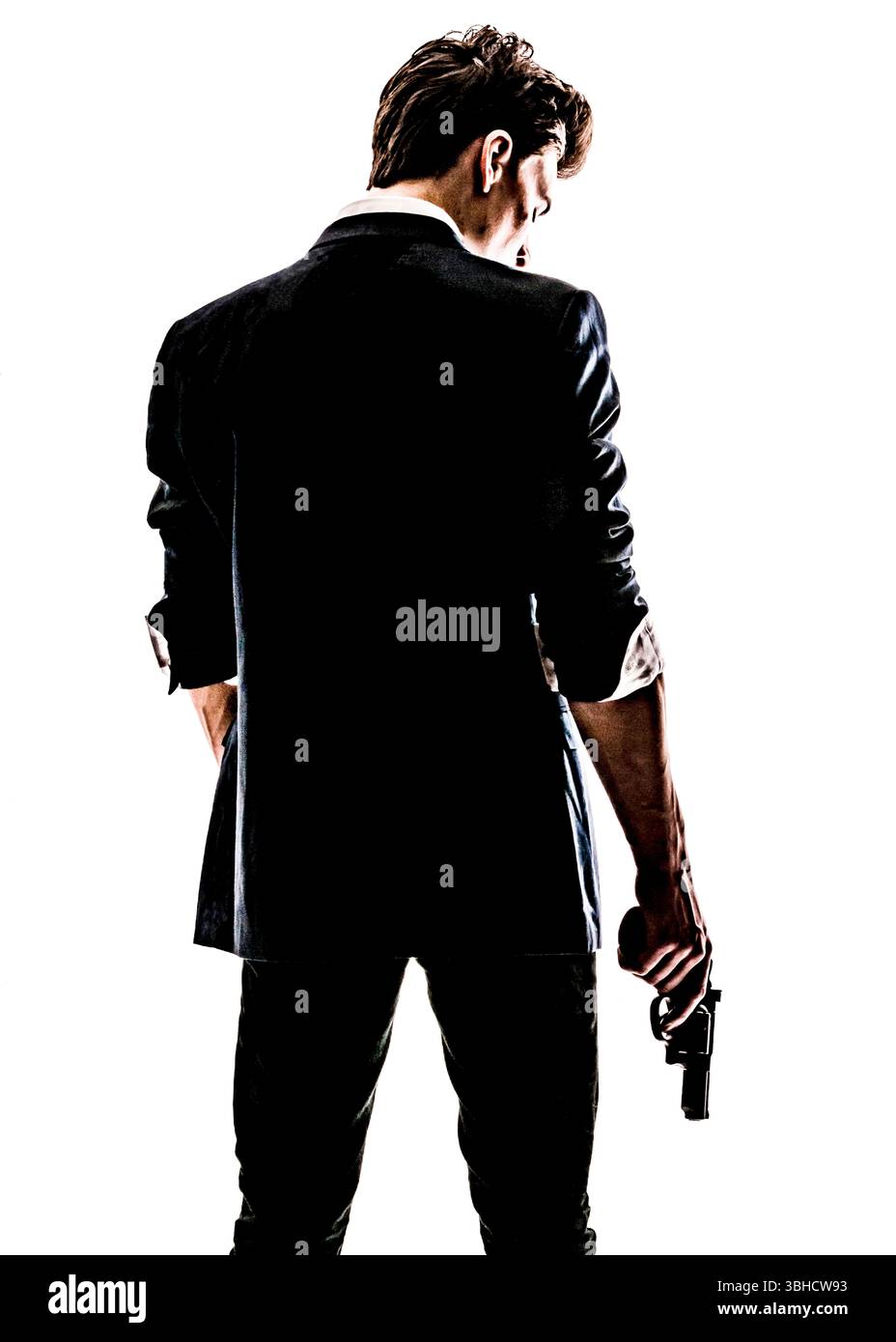 A man in a suit, seen from the back, holds a gun by his side. His head ...