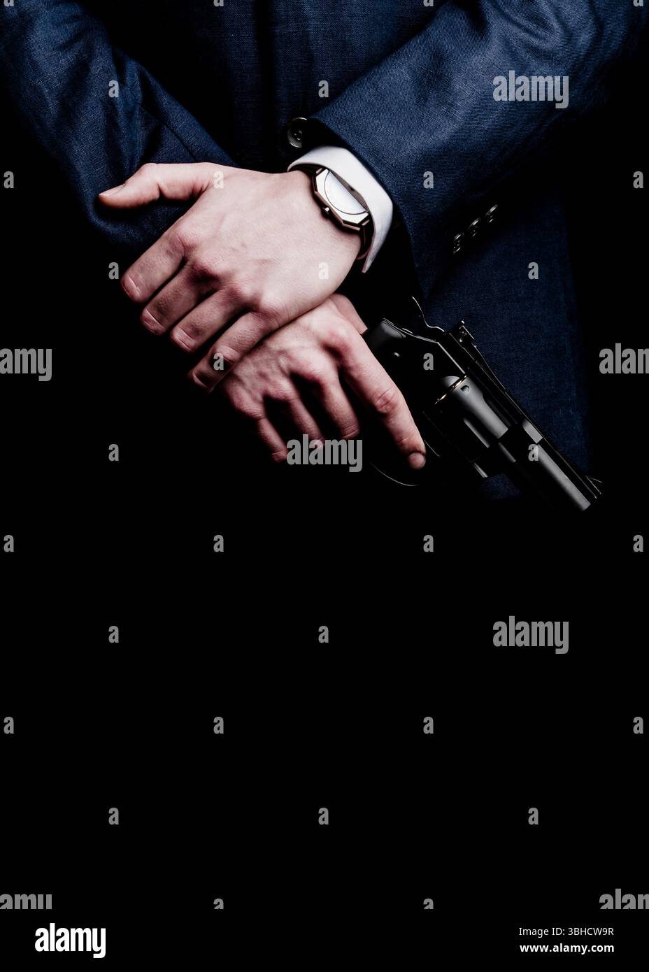 A man in a suit holds a revolver behind his back Stock Photo - Alamy