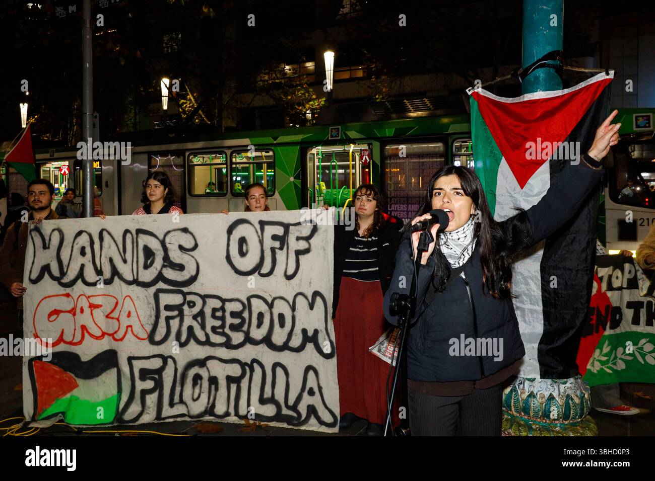 A protester raises her hand and shouts slogans into a microphone during ...