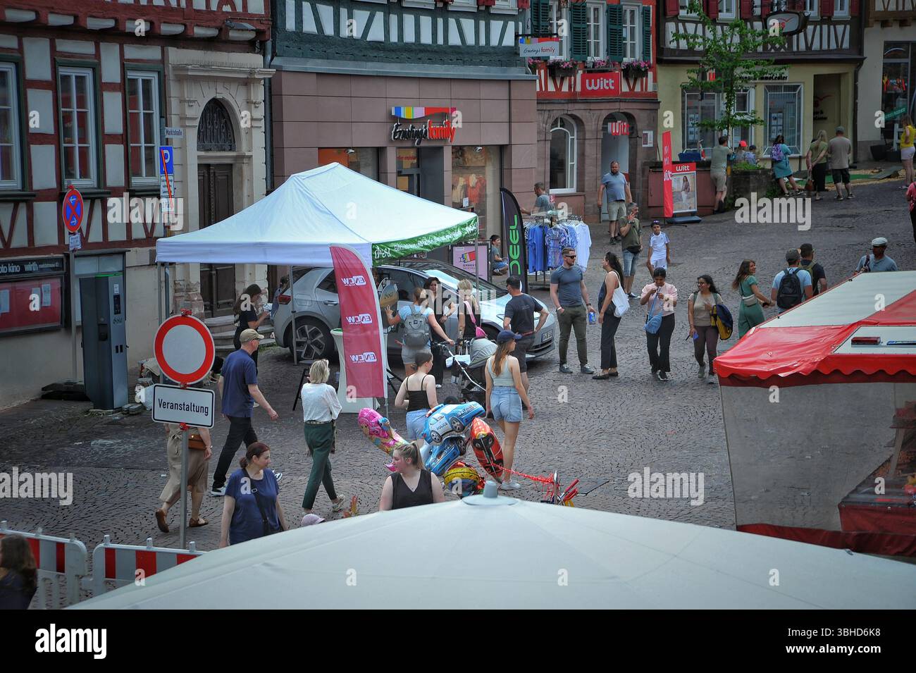 The image captures a vibrant town square with historic half-timbered ...