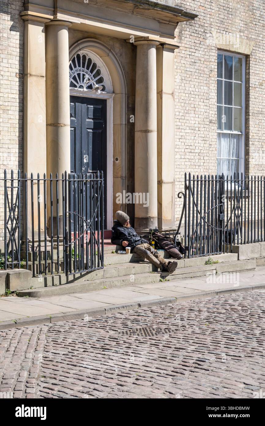 Homeless man resting in sunshine on steps of building, Castle Hill ...