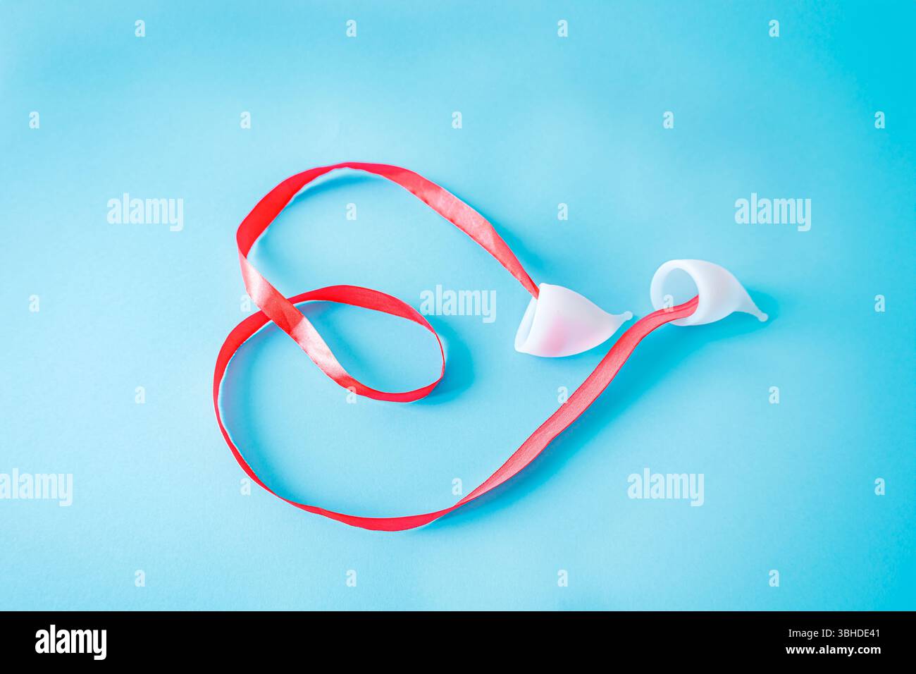 Two menstrual cups connected by a red ribbon forming a symbolic shape ...