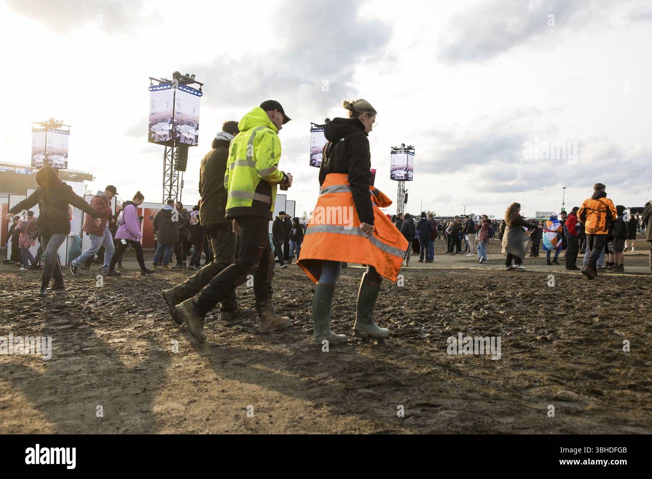 Festival visitors walk through mud in the evening sun at the Rock am ...