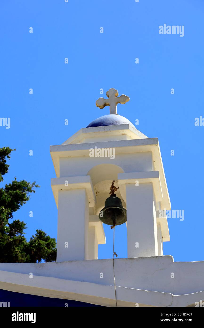 White Greek church bell tower and cross against blue sky, Triantaros ...