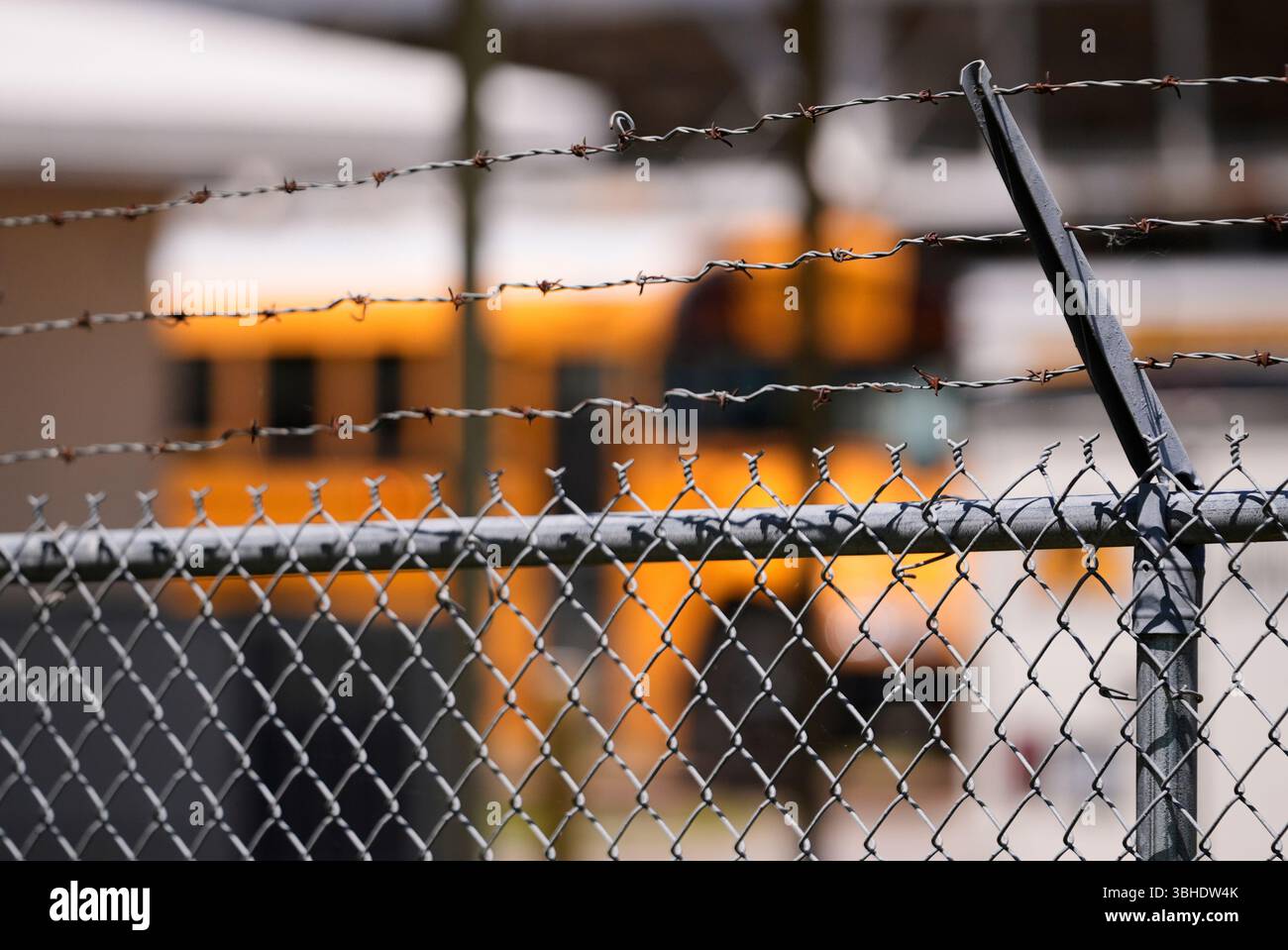A school bus is seen behind a fence with barbed wire outside Ferriday ...