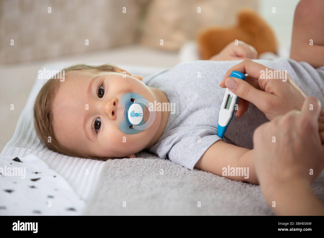 baby sucking dummy has a thermometer under the arm Stock Photo - Alamy
