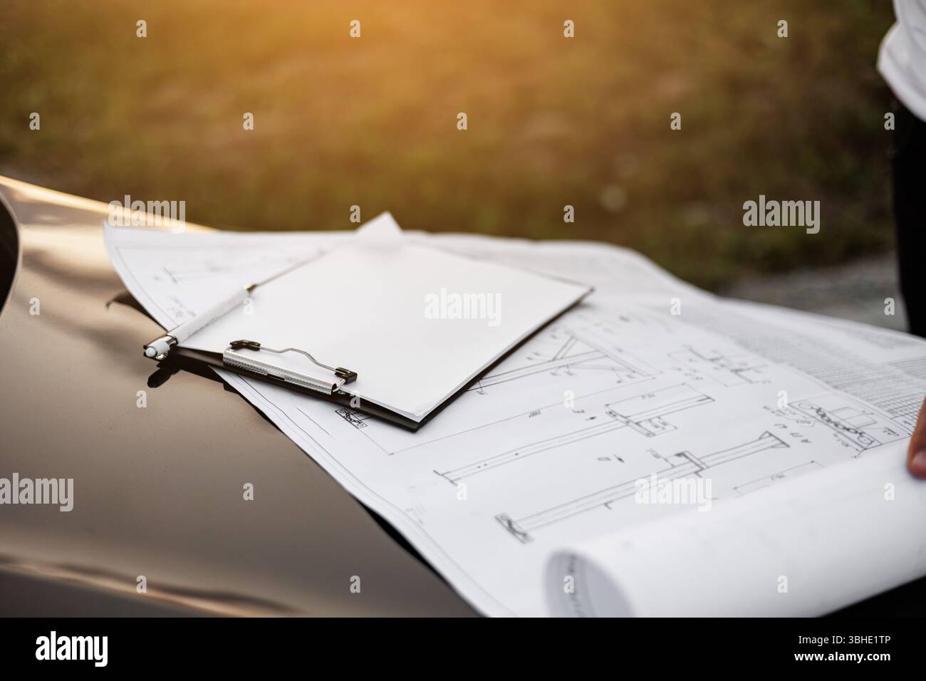 View on blueprints of construction, clipboard with notes at car hood at ...