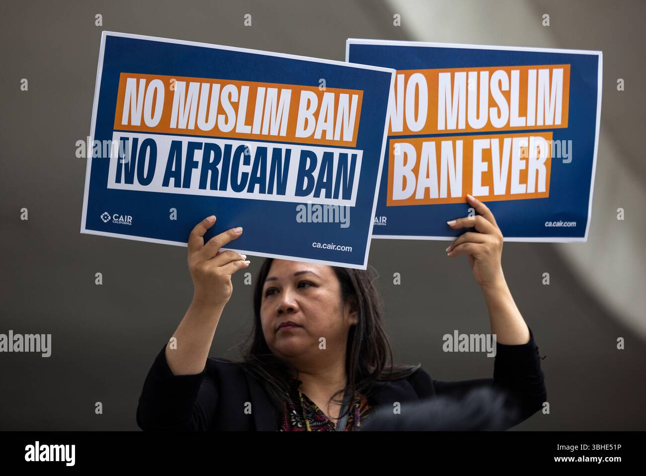 A demonstrator holds posters during a protest against new travel ban ...
