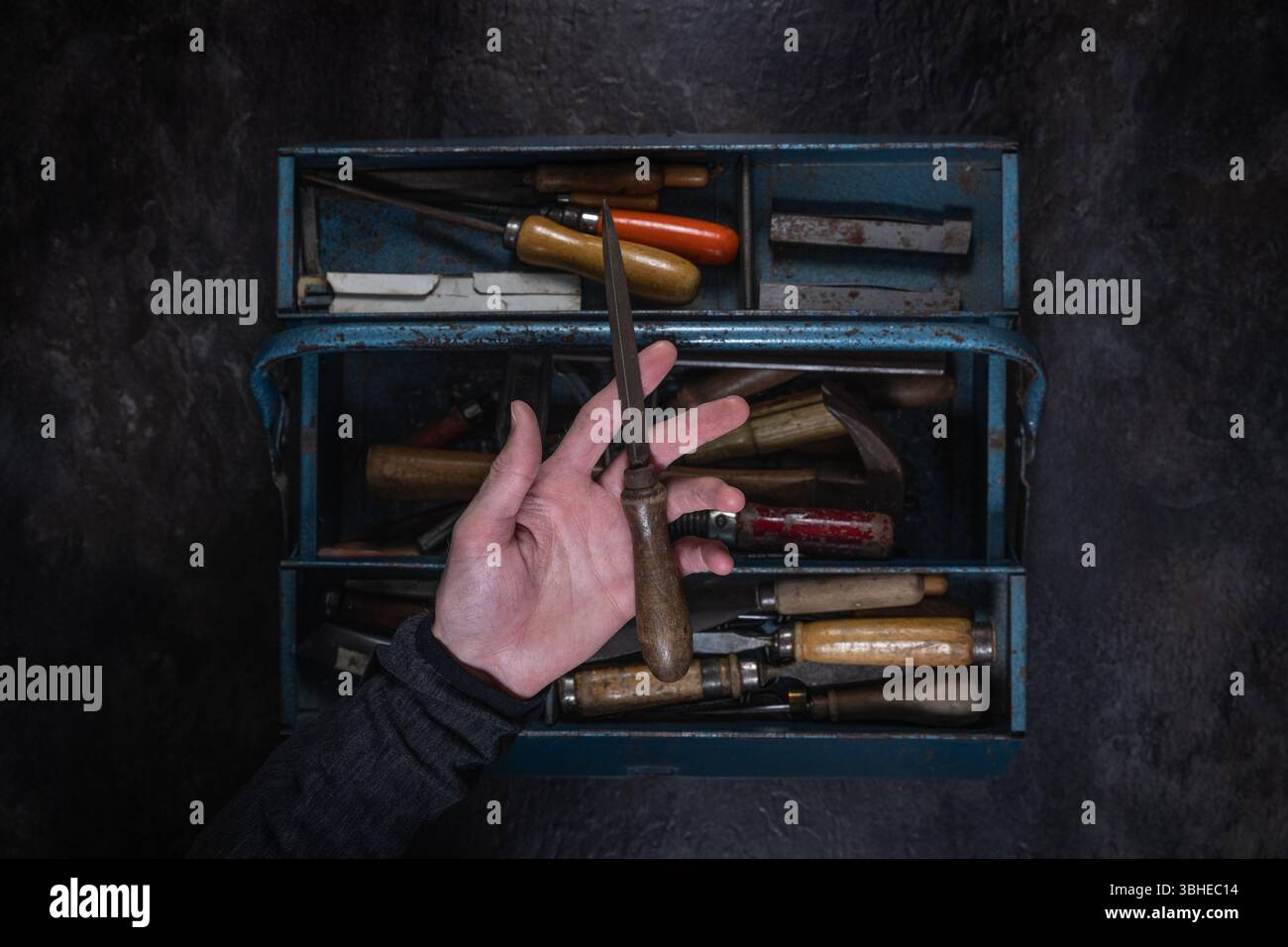 Old metal file with wooden handle held by hand in focus, blurred open ...