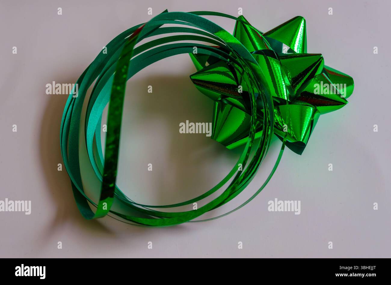 A single green present bow and looped ribbon isolated on a white ...