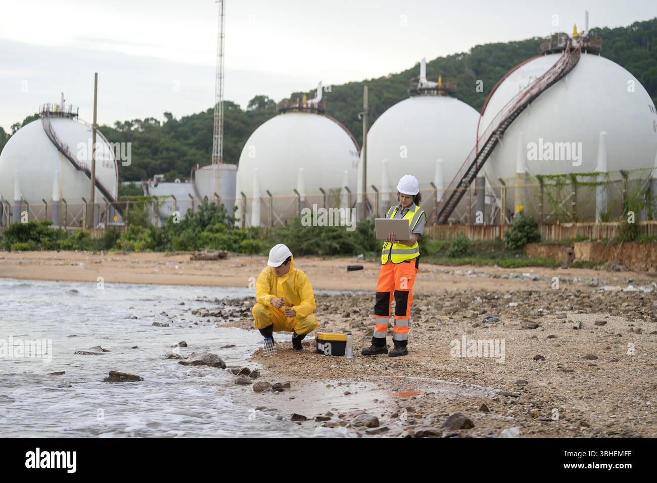 Two workers conduct an environmental assessment along a shoreline. They ...