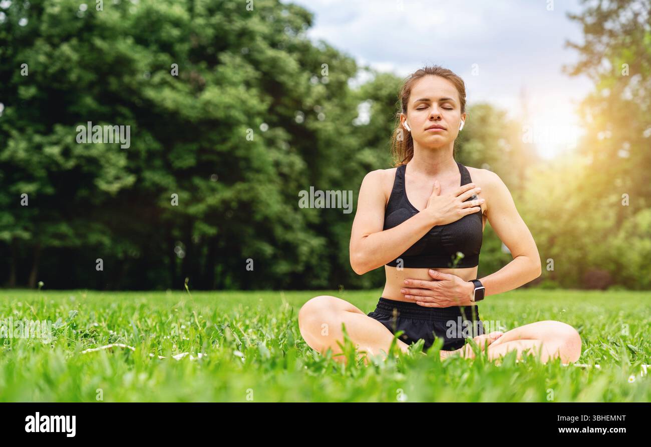 Healthy woman practising breathing exercise in lotus pose in urban park ...