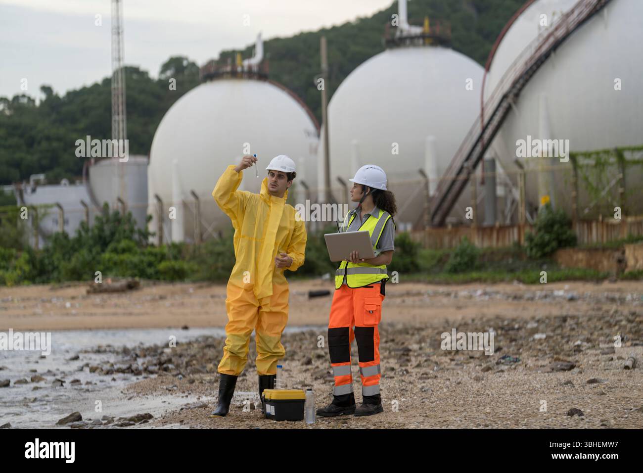 Two environmental scientists are engaged in water sampling near ...