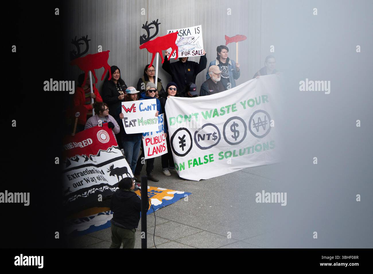 People hold signs during a protest outside the annual Alaska ...
