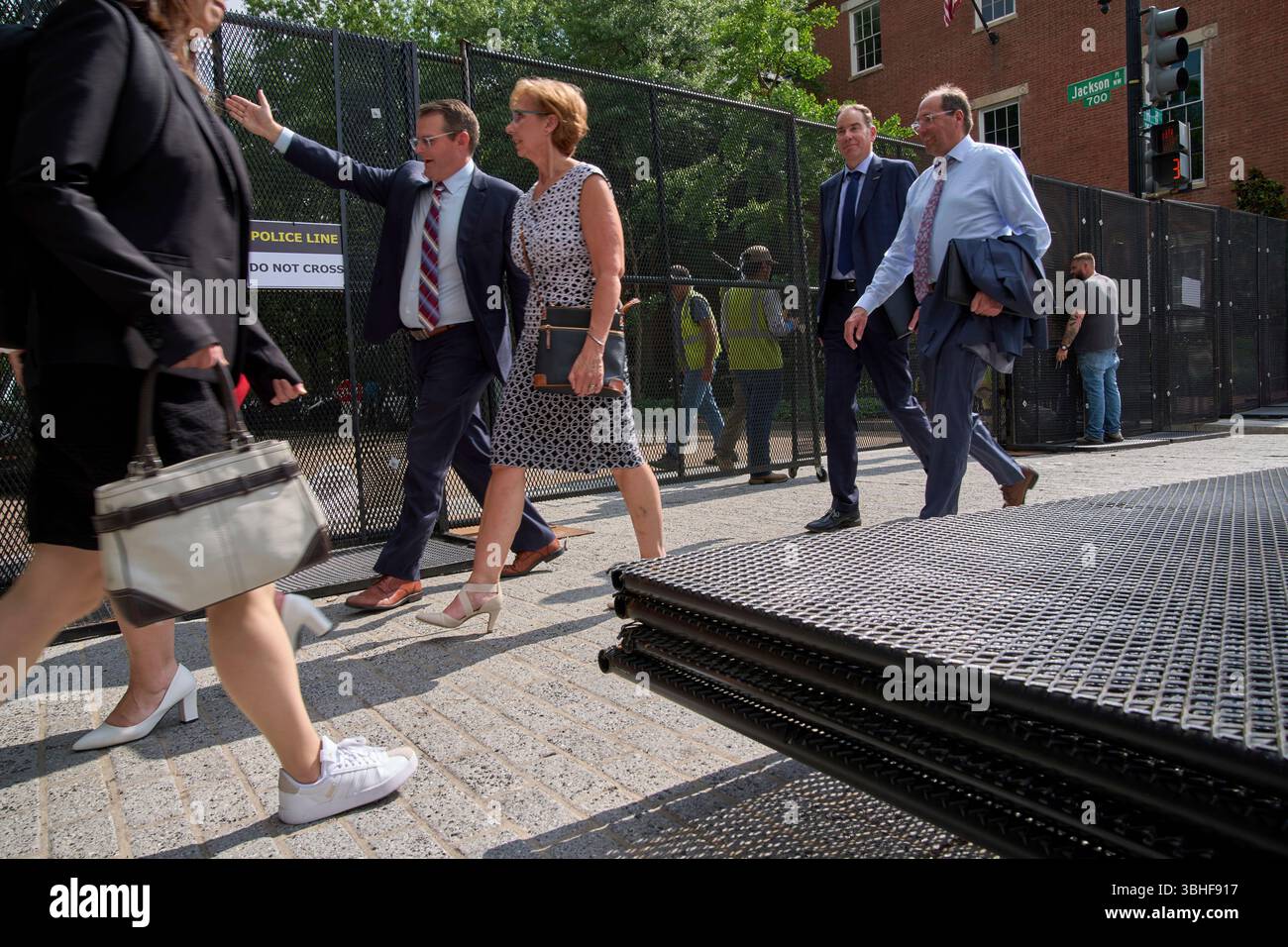 People walk by security fencing as it is installed around Lafayette ...