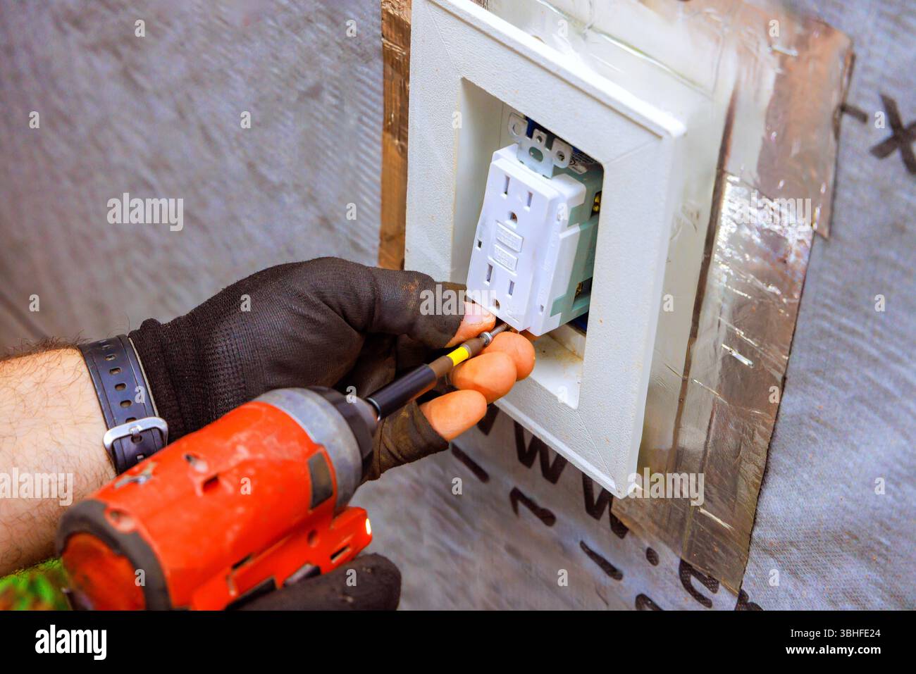 An electrician works on installing an electrical outlet in home ...