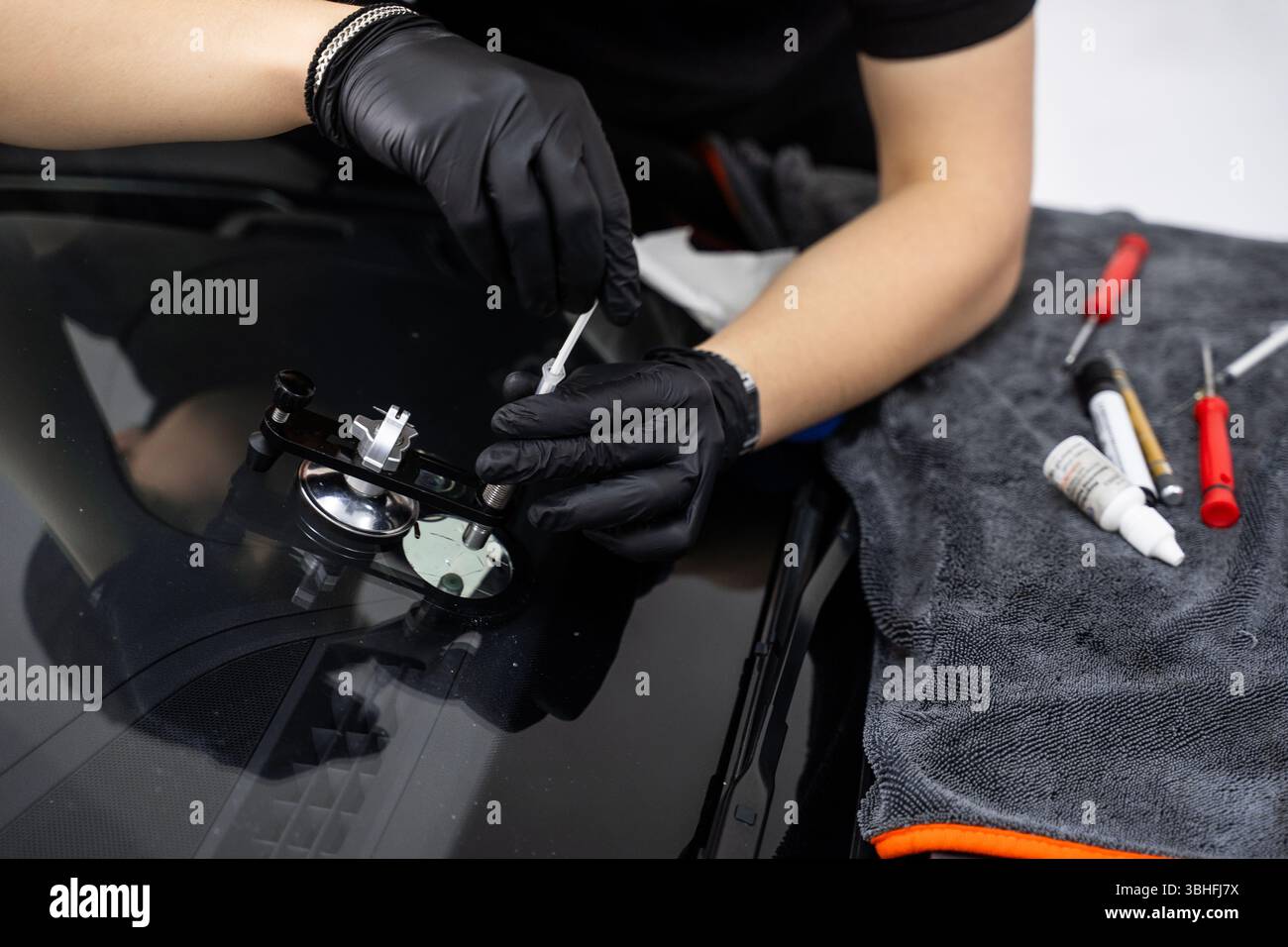 Windshield crack repair using resin injection. Technician using ...