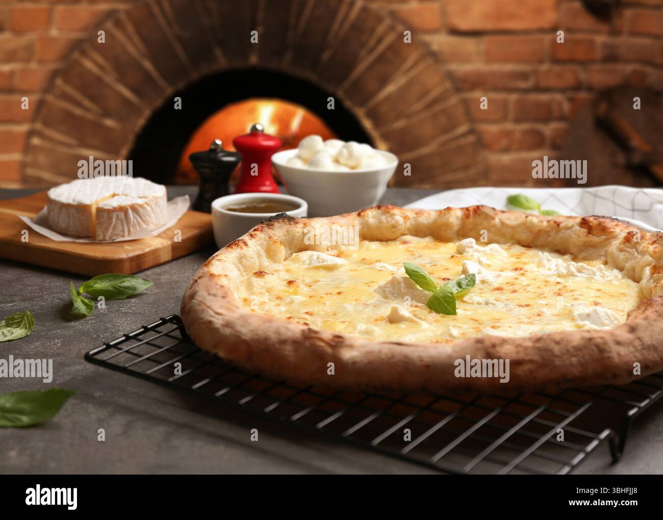 Delicious hot cheese pizza and ingredients on grey table against oven ...