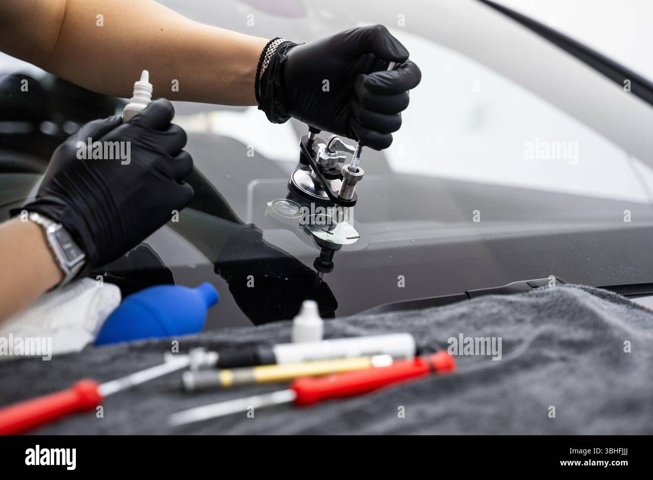 Windshield crack repair using resin injection. Technician using ...