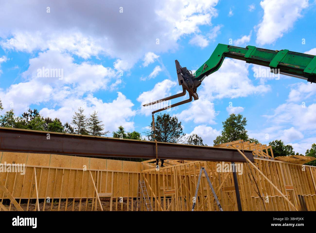 Heavy telehandler machinery lifts steel beam at construction site ...