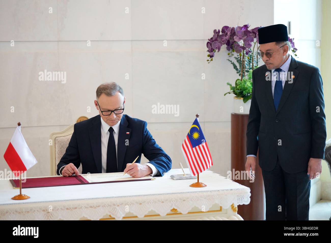 Poland's outgoing President Andrzej Duda, left, signs on a guest book as Malaysian Prime ...
